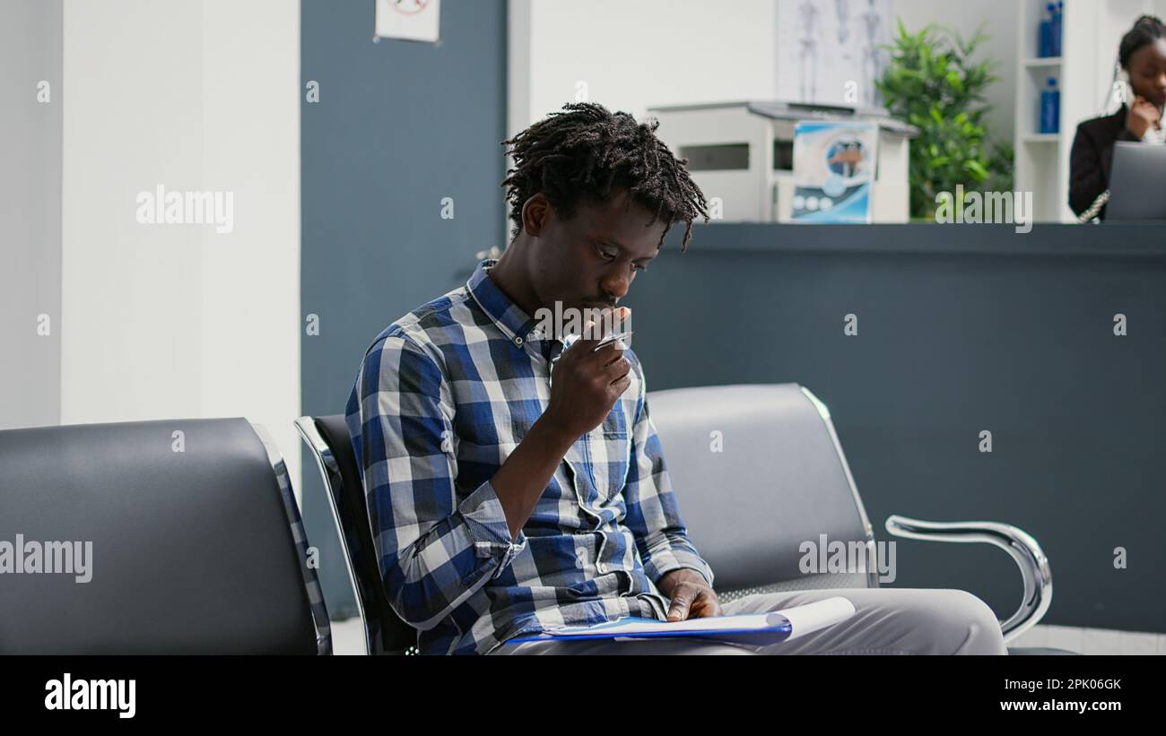 African american patient filling in checkup report papers, sitting in ...