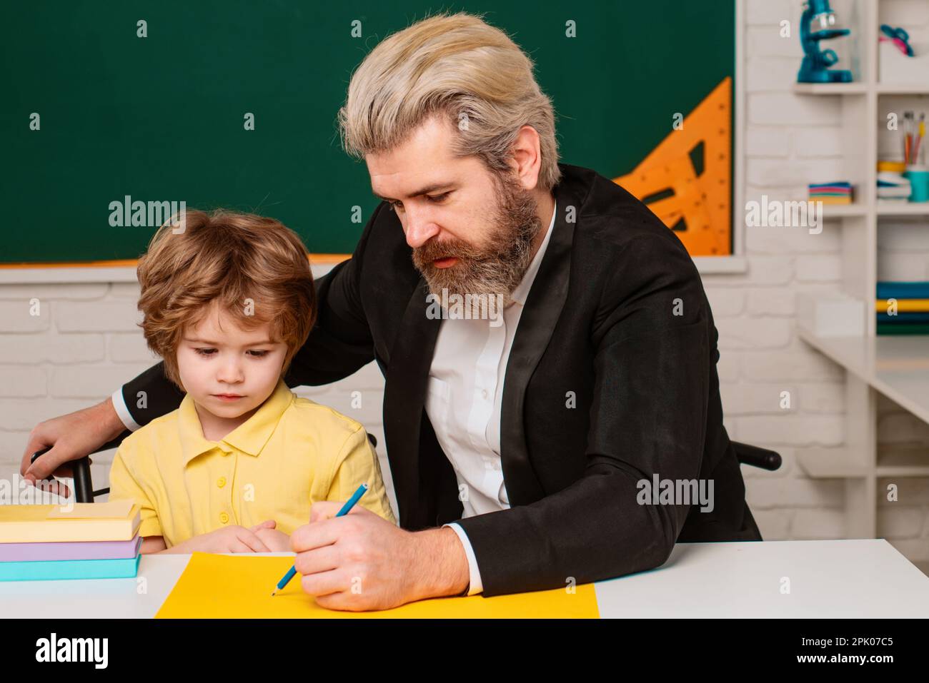 Father teaching son. Cute little preschool kid boy with teacher study in a classroom. Private ...