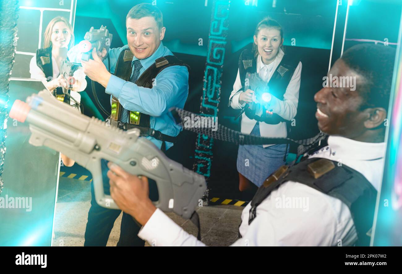 Group of colleagues holding laser pistols playing laser tag game Stock ...