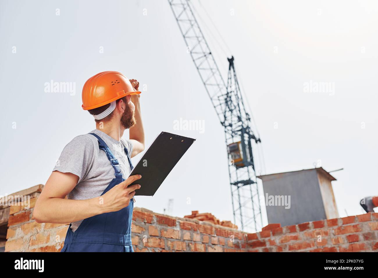 With documents in the black notepad. Young construction worker in ...