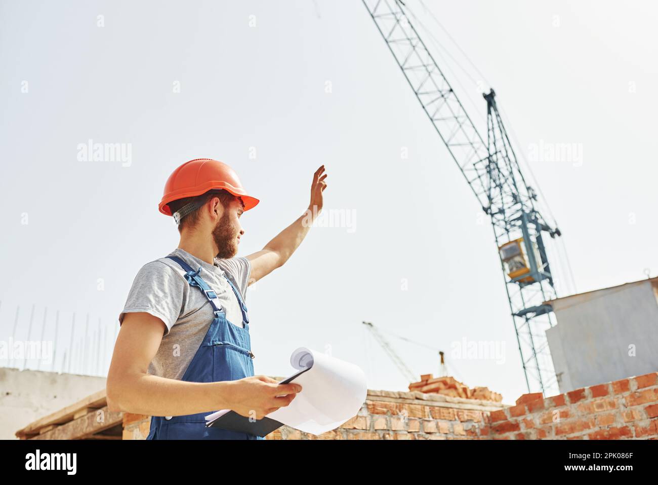 Some paperwork. Young construction worker in uniform is busy at the ...