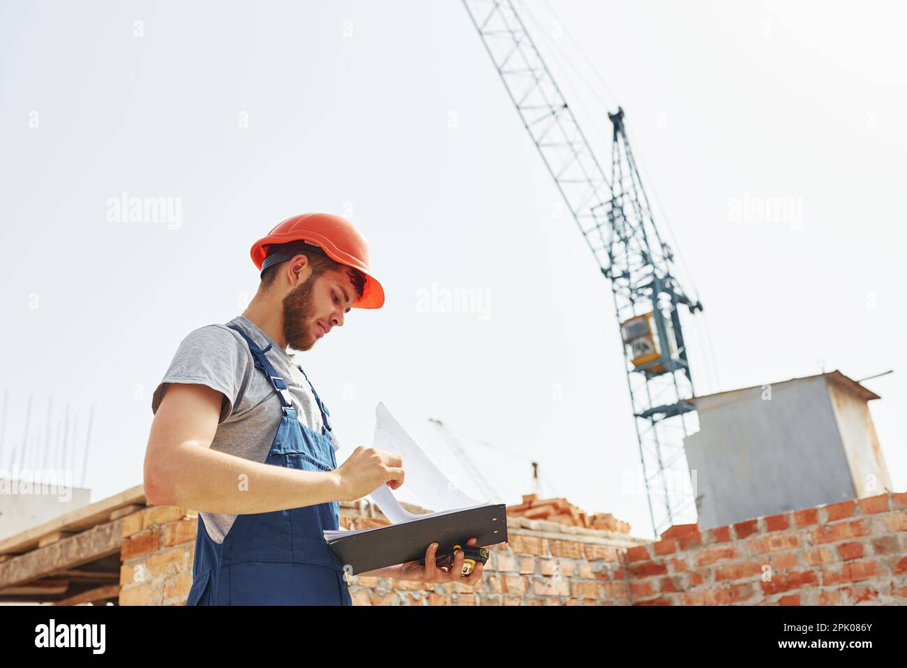 Some paperwork. Young construction worker in uniform is busy at the ...
