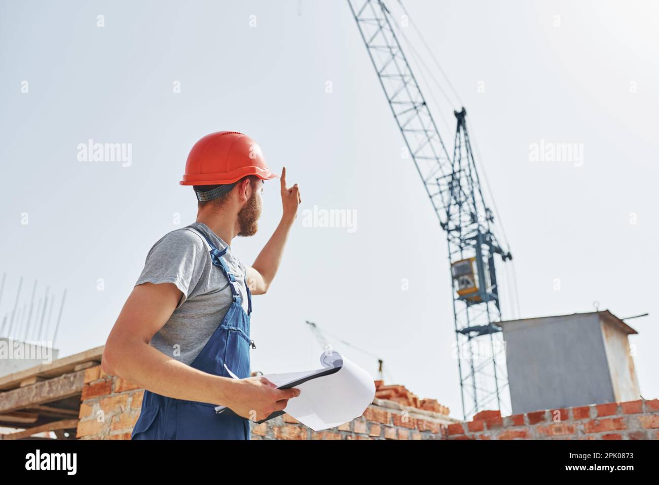 Some paperwork. Young construction worker in uniform is busy at the ...