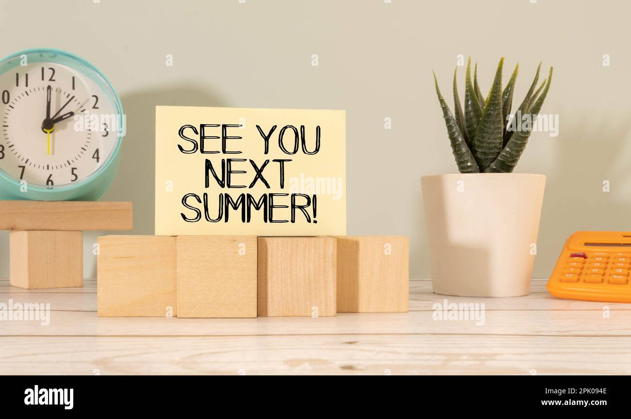 See you next Summer written on a note at the office table with empty ...