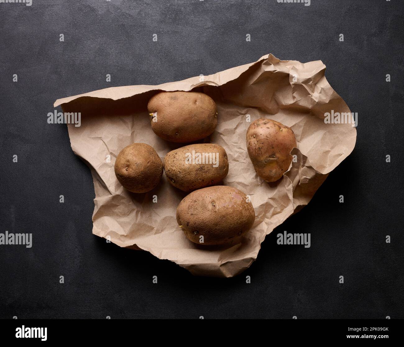 Raw potatoes lie on a brown piece of paper, top view Stock Photo - Alamy