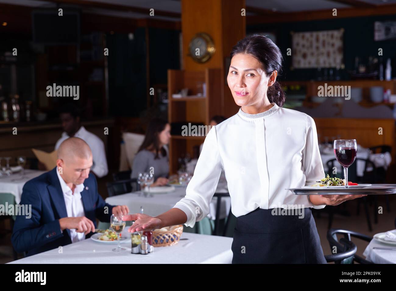 Polite waitress with serving tray warmly welcoming in restaurant Stock ...