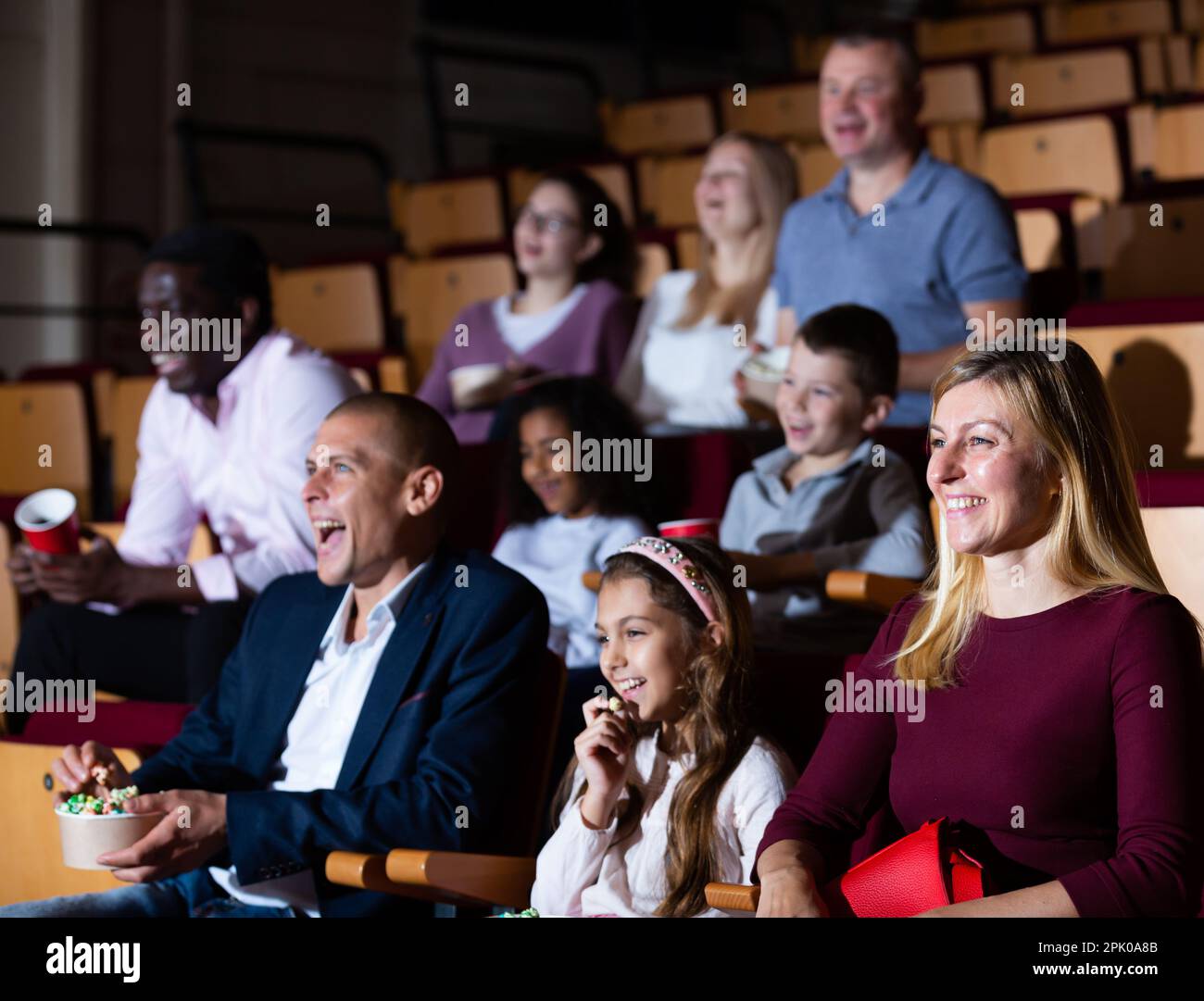 Friendly family laughing while watching funny movie in cinema Stock ...