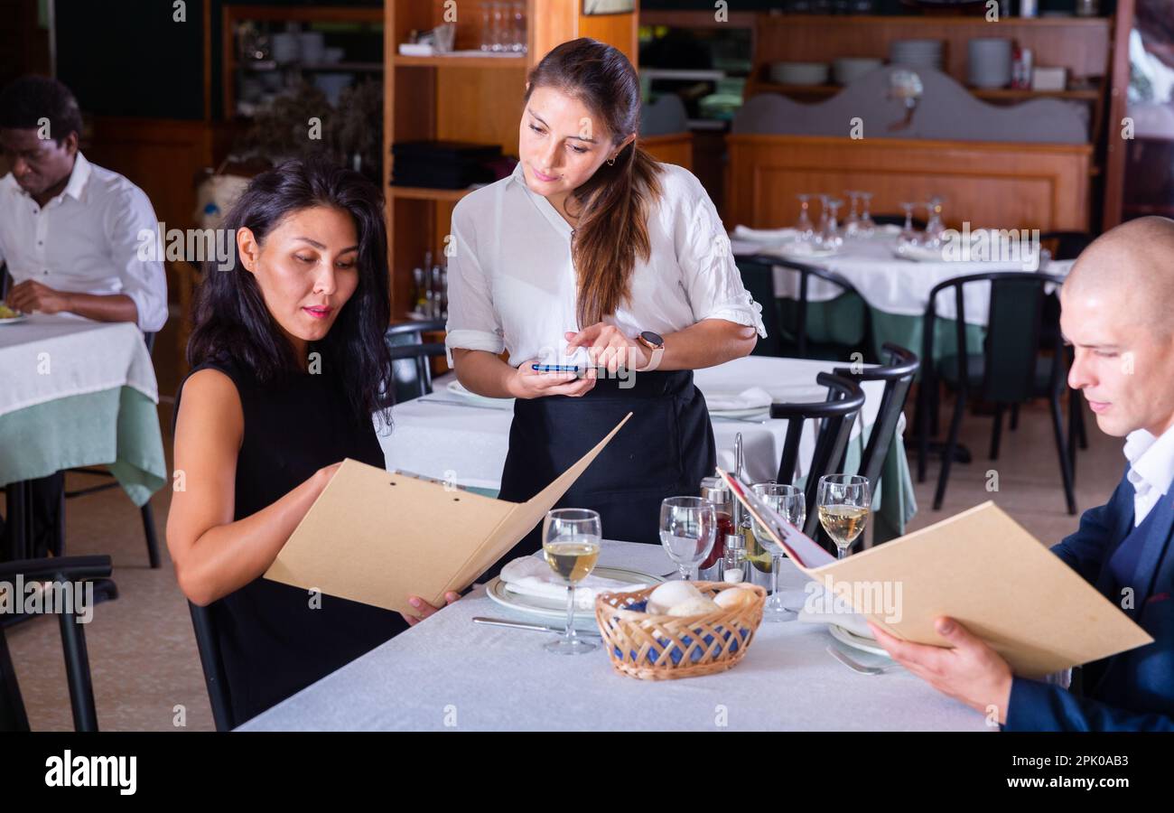 Couple making order with hospitable waitress in restaurant Stock Photo ...