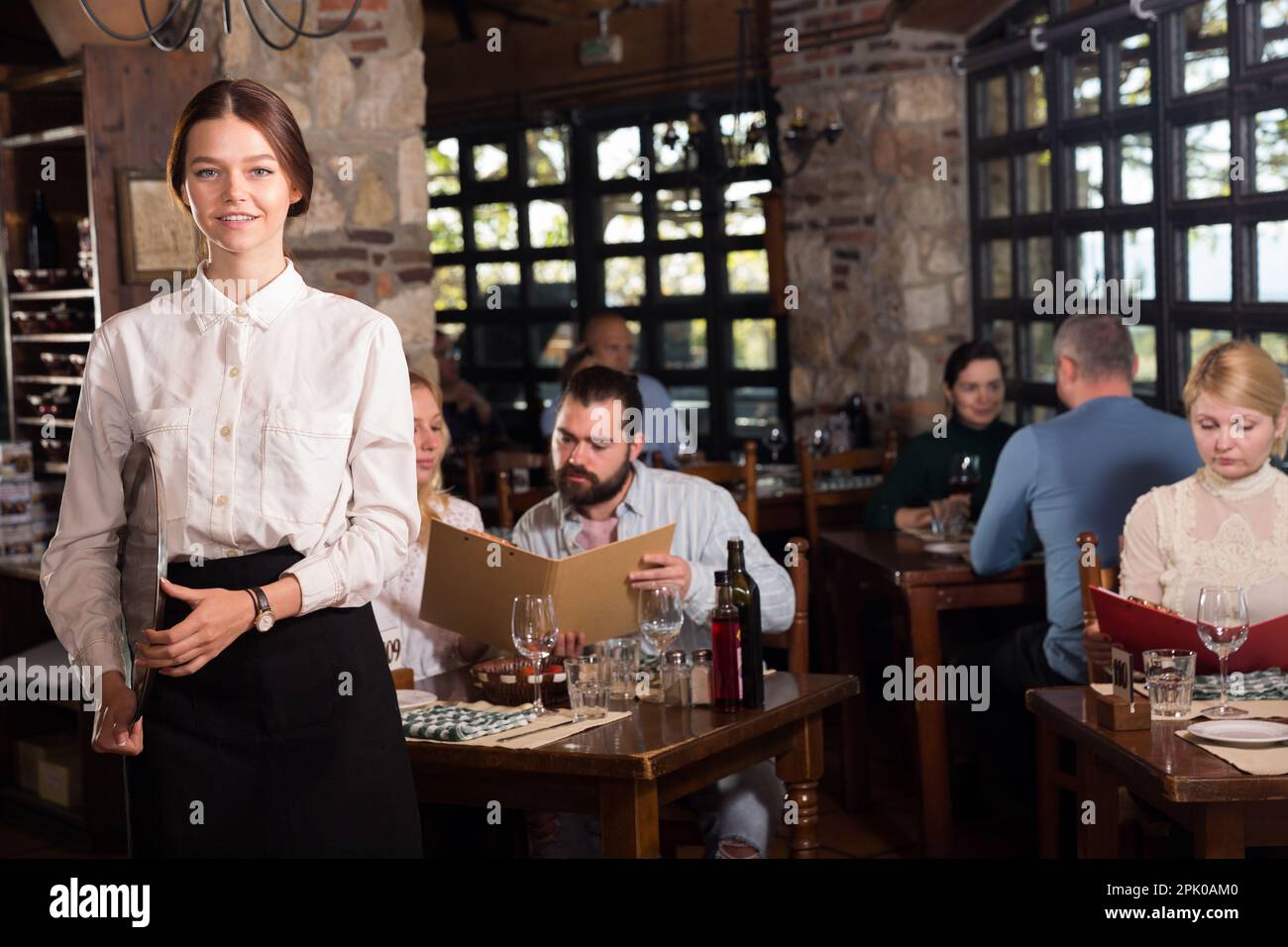 Female owner of country restaurant meeting guests Stock Photo - Alamy