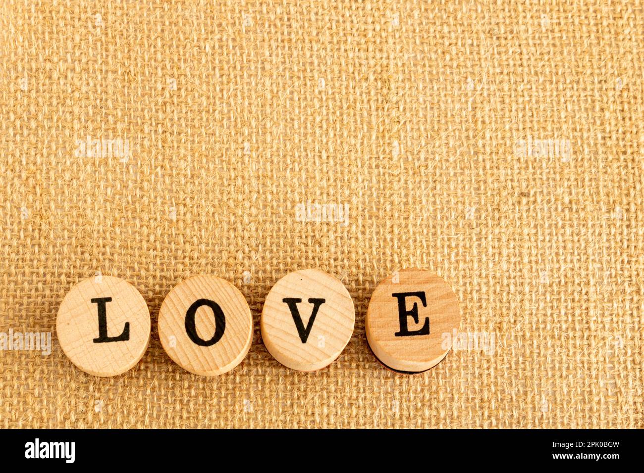 round pieces of wood that form the word Love in black on a brown jute ...