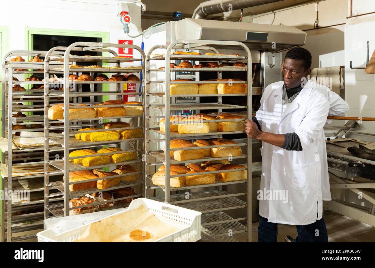 Baker pushing trolley with baked bread Stock Photo - Alamy
