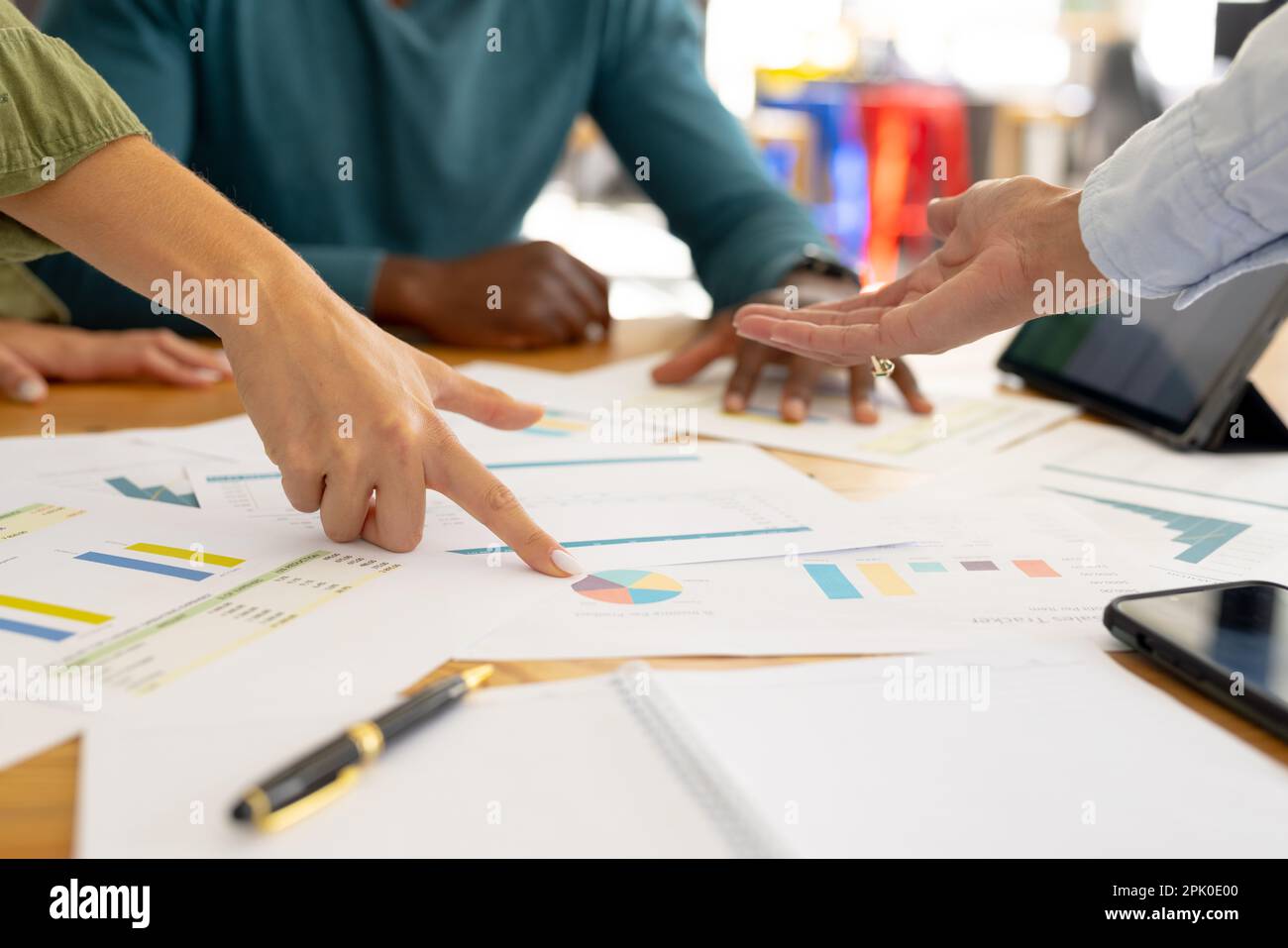 Diverse group of casual architects discussing graphs on table in modern ...