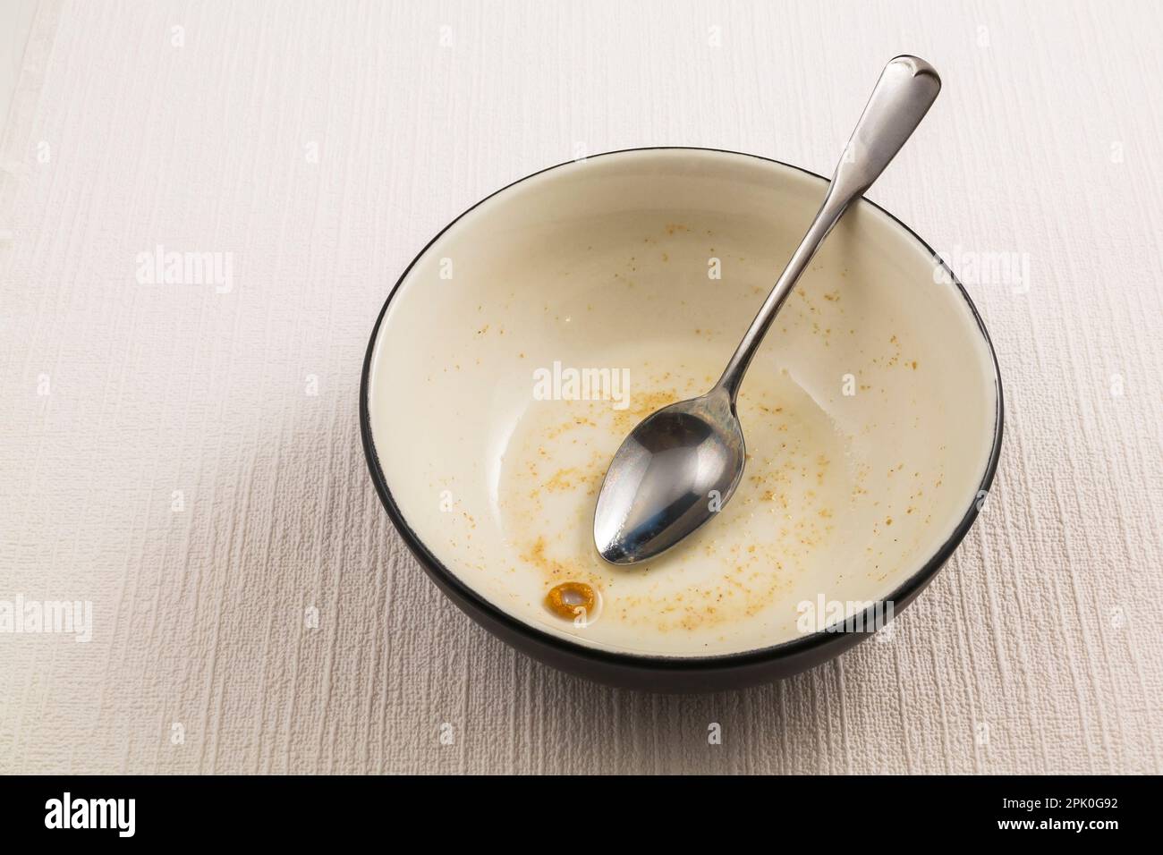 Almost empty bowl of cereal with spoon on white textured background Stock Photo - Alamy