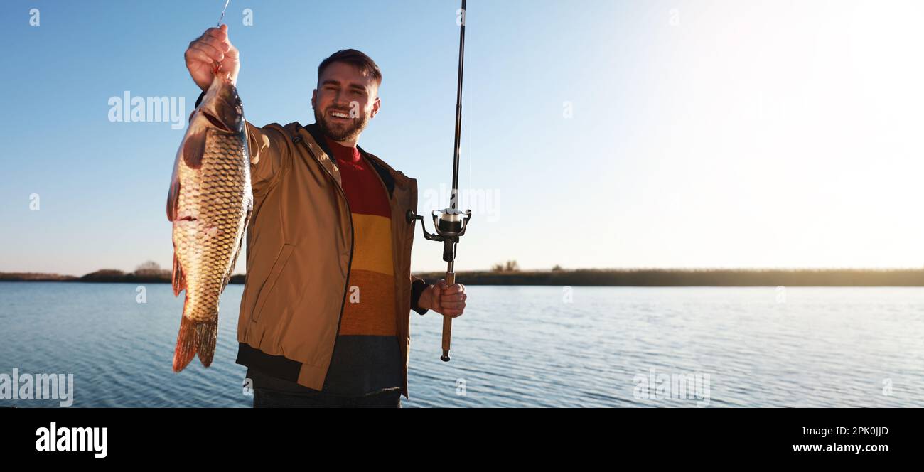 Fisherman holding fishing rod and catch at riverside, space for text ...