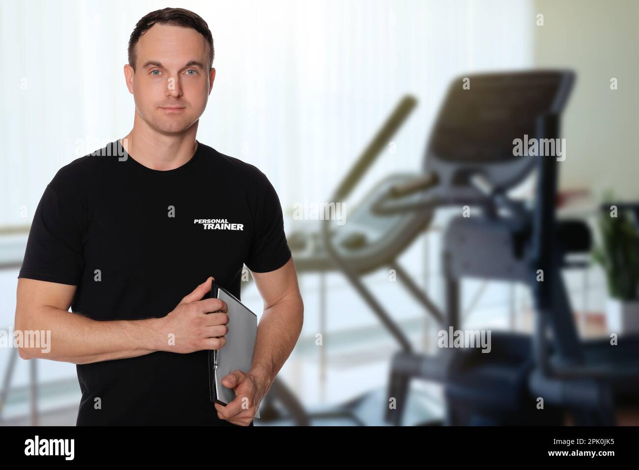 Portrait of professional personal trainer with clipboard in gym. Space ...