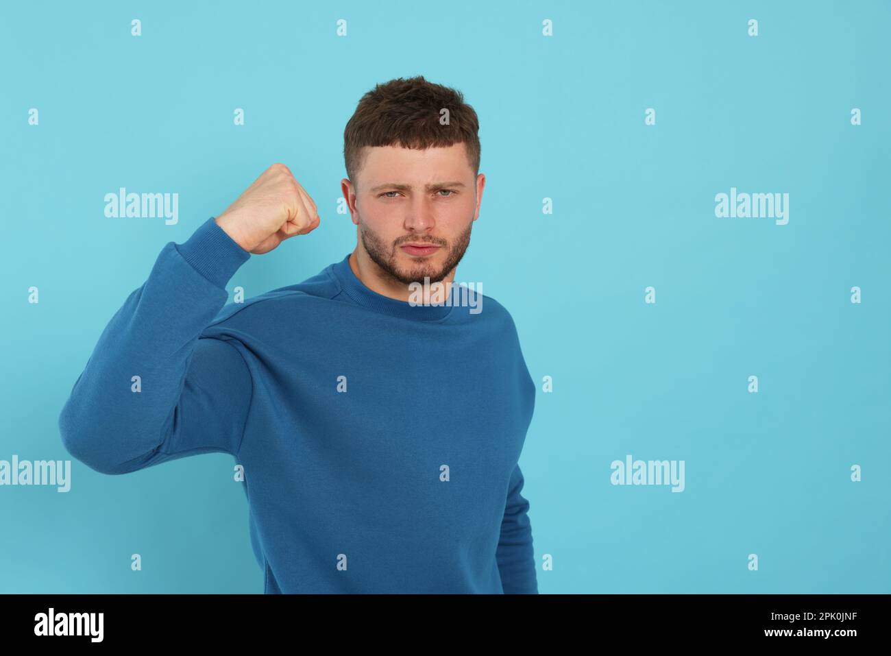 Aggressive young man on light blue background, Space for text Stock ...