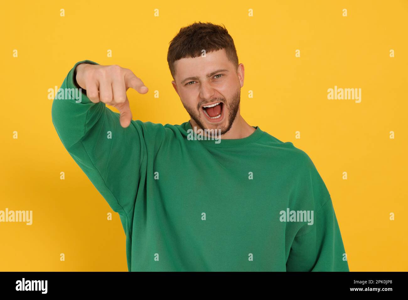 Aggressive young man shouting on orange background Stock Photo - Alamy