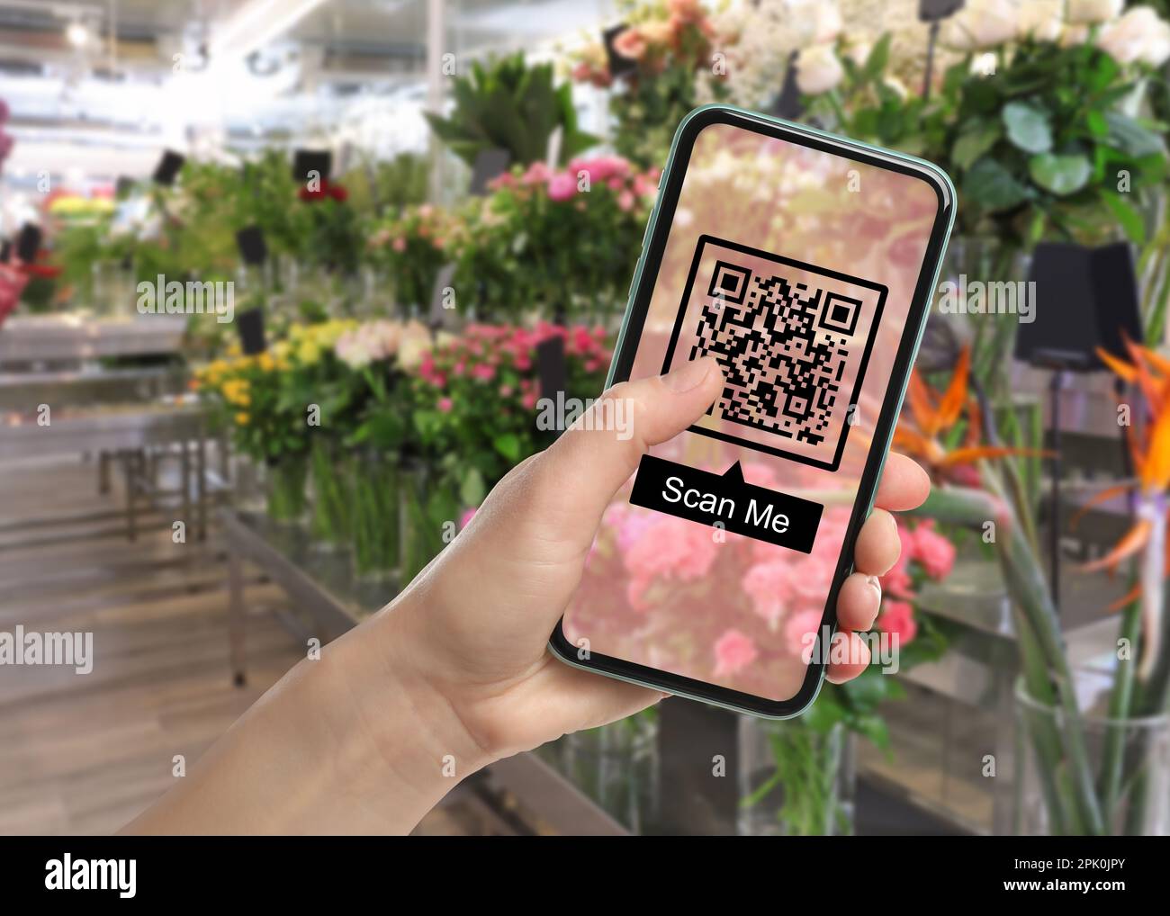 Woman holding smartphone with QR code on screen in flower shop, closeup ...