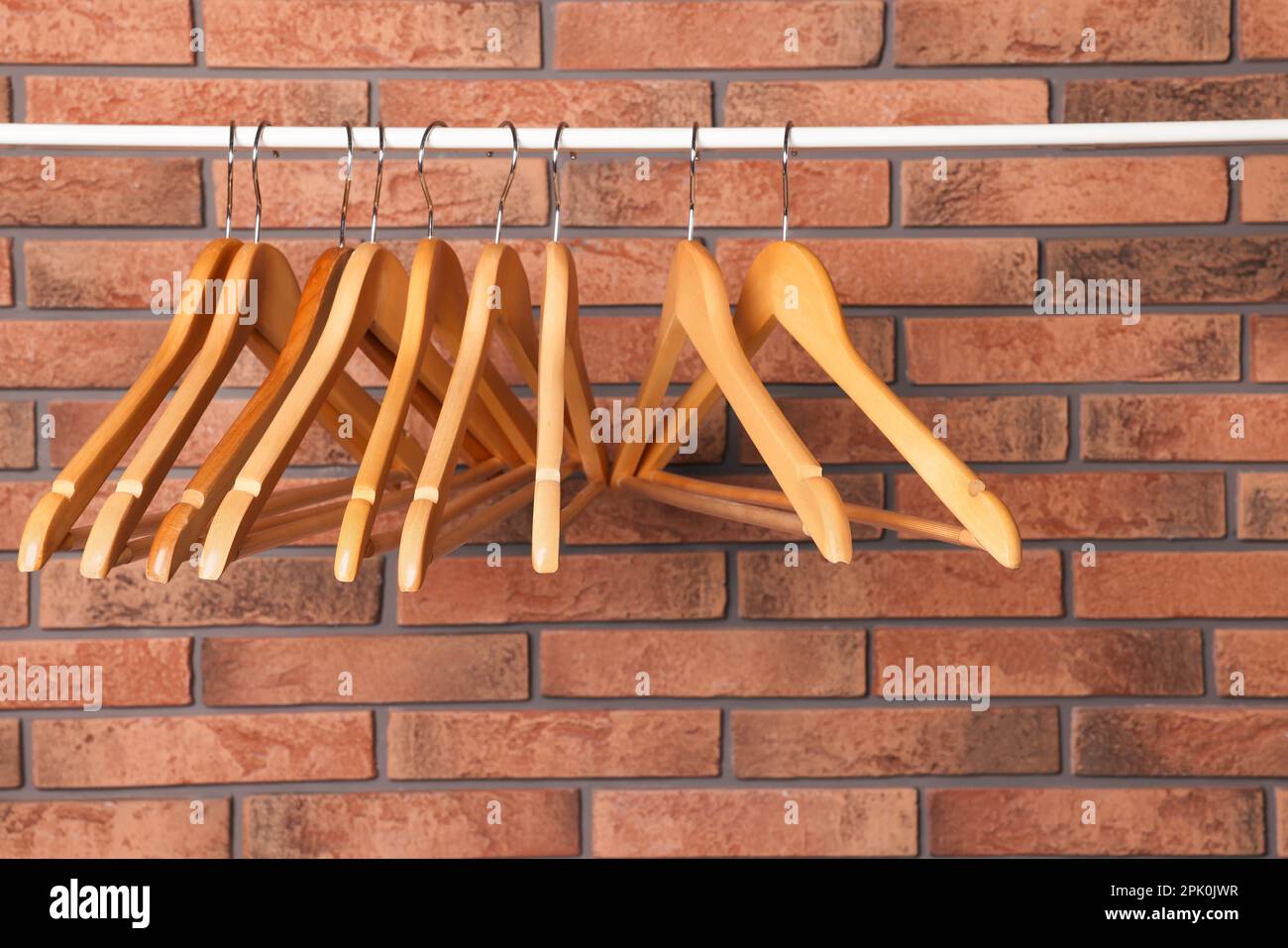 Wooden clothes hangers on rail near red brick wall Stock Photo - Alamy