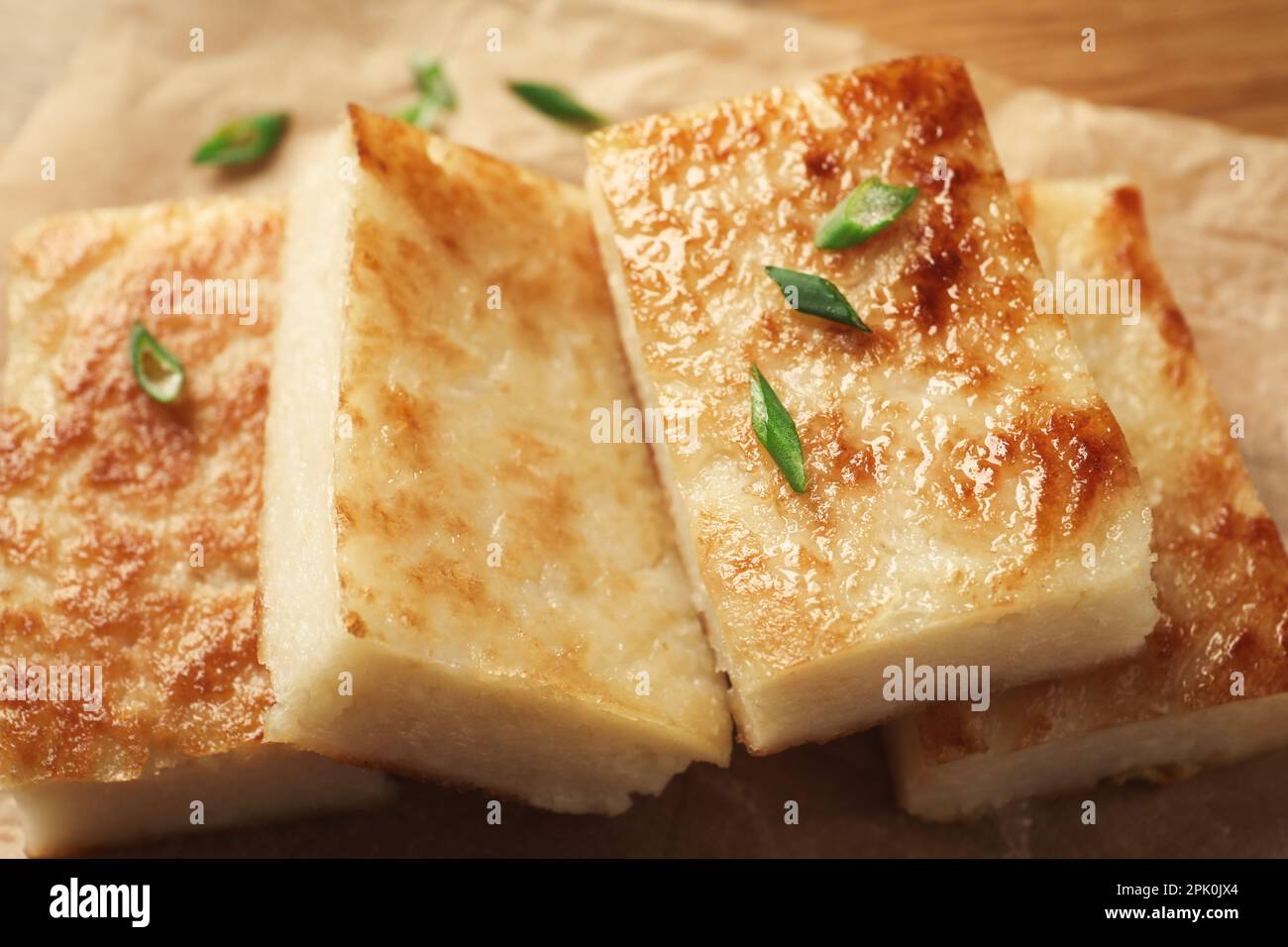 Delicious turnip cake with green onion on parchment paper, closeup ...
