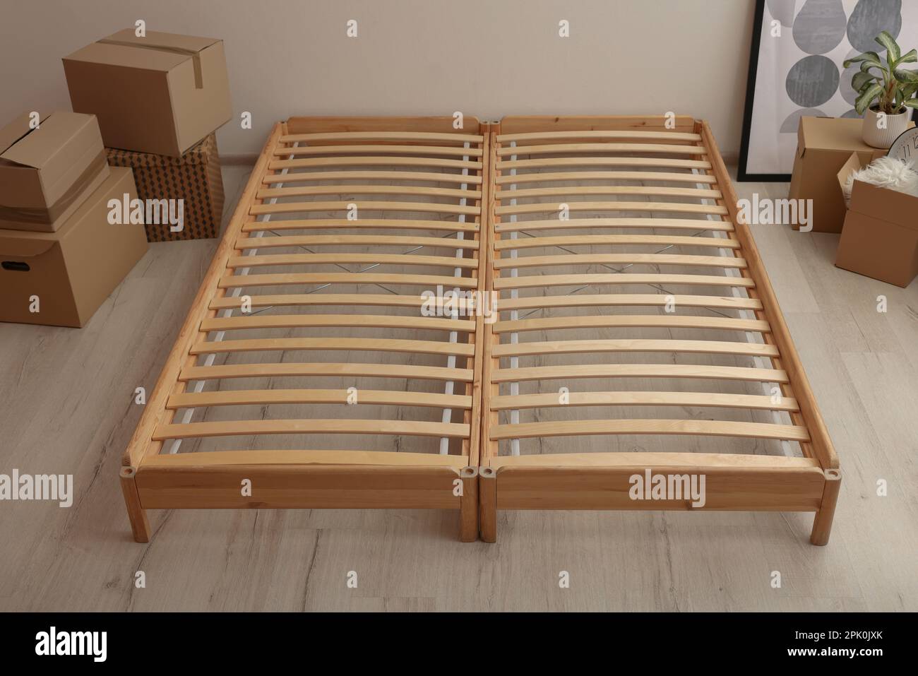 Wooden bed frame and cardboard boxes on floor in room Stock Photo - Alamy