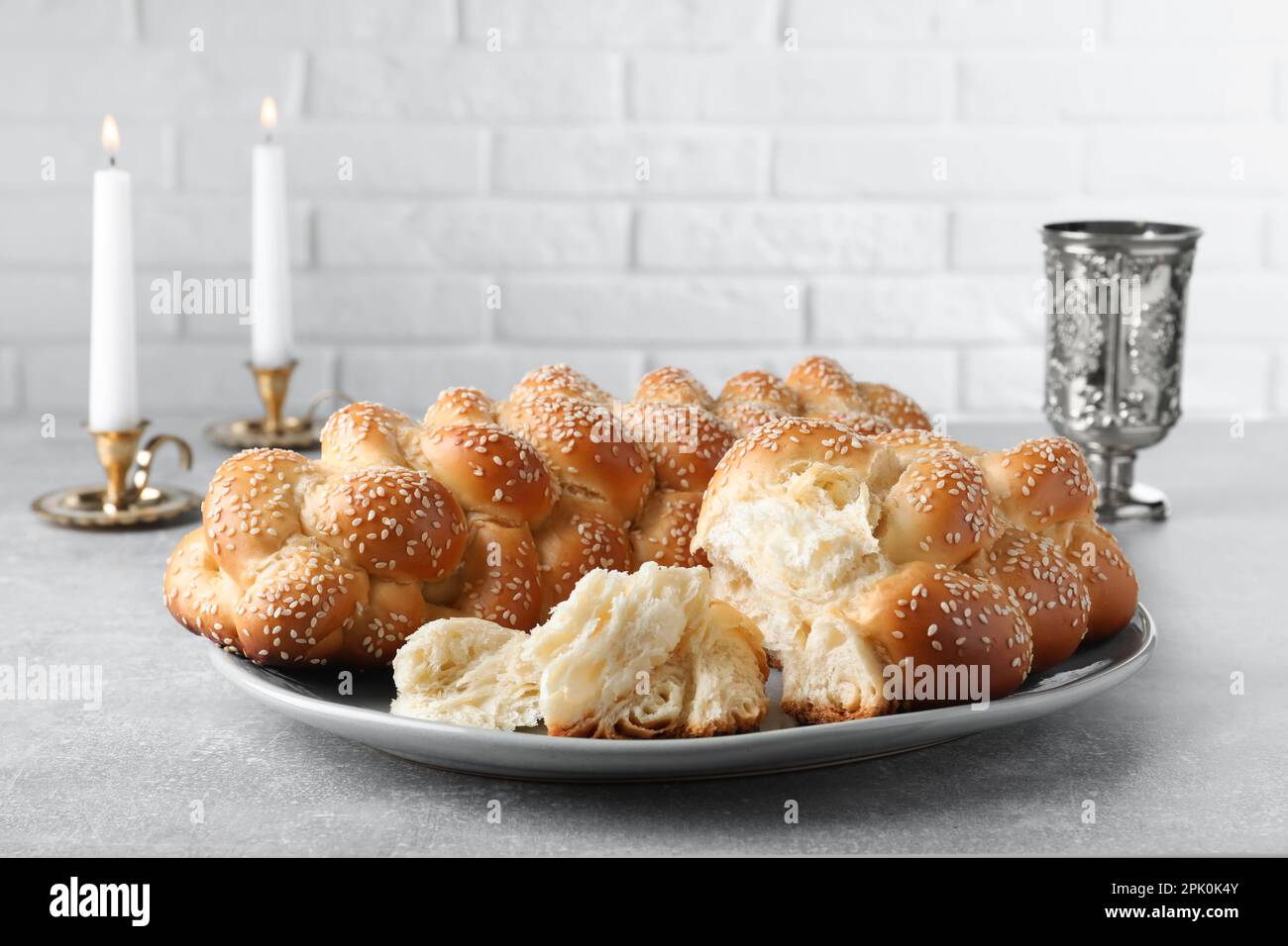 Homemade braided bread with sesame seeds, goblet and candles on grey ...