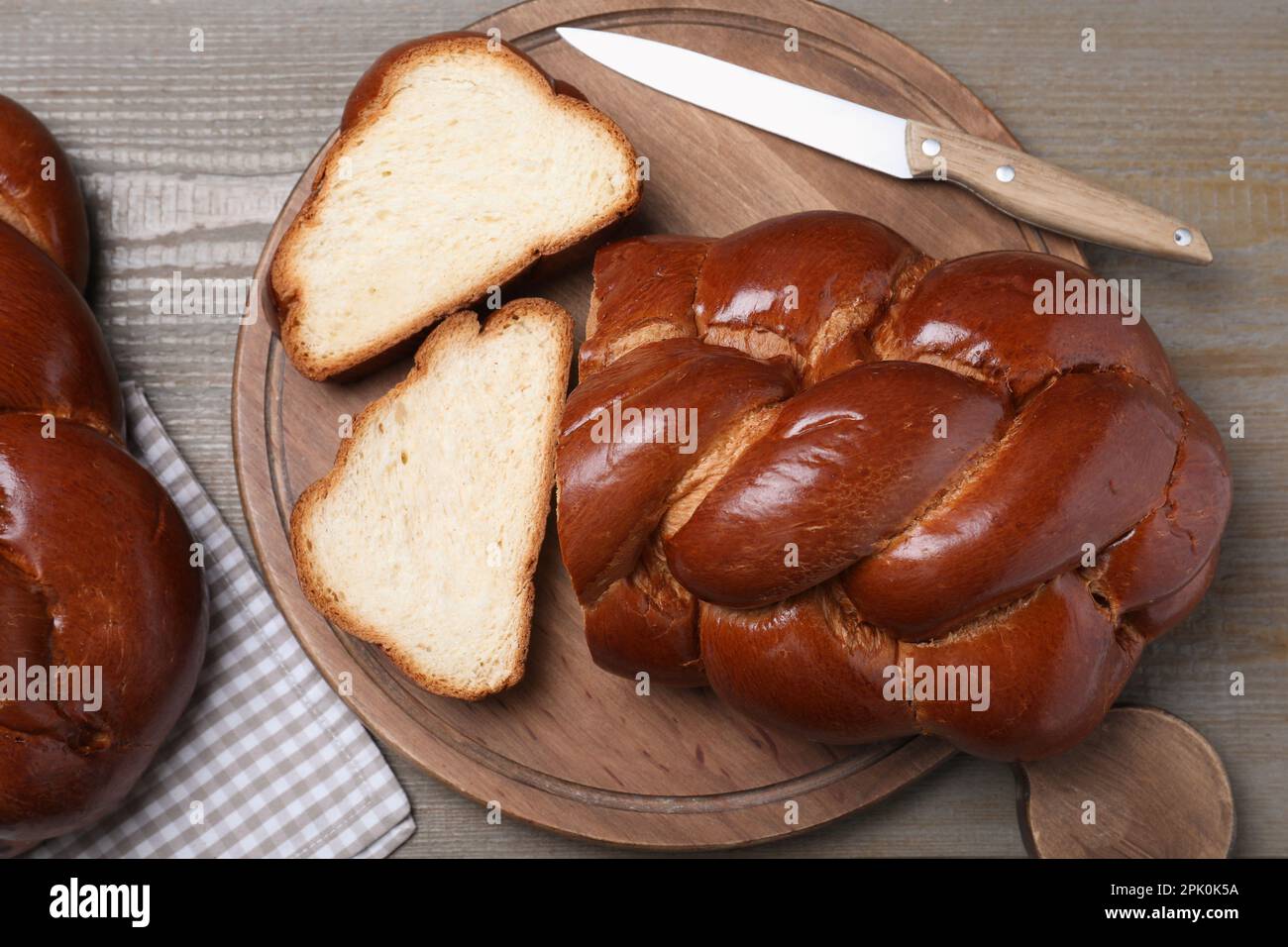 Cut homemade braided bread and knife on wooden table, flat lay. Challah ...