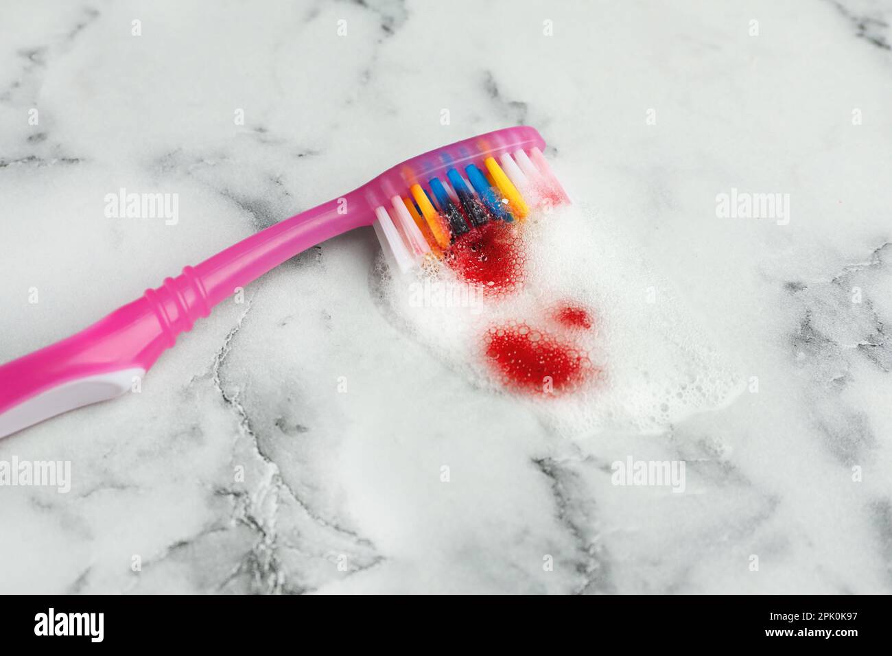 Brush and toothpaste foam with blood on white marble table, closeup ...