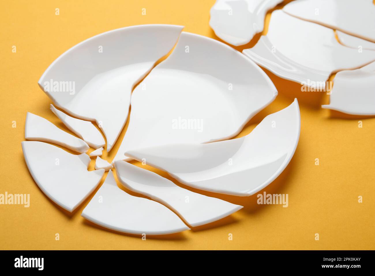 Two broken ceramic plates on orange background, closeup Stock Photo - Alamy