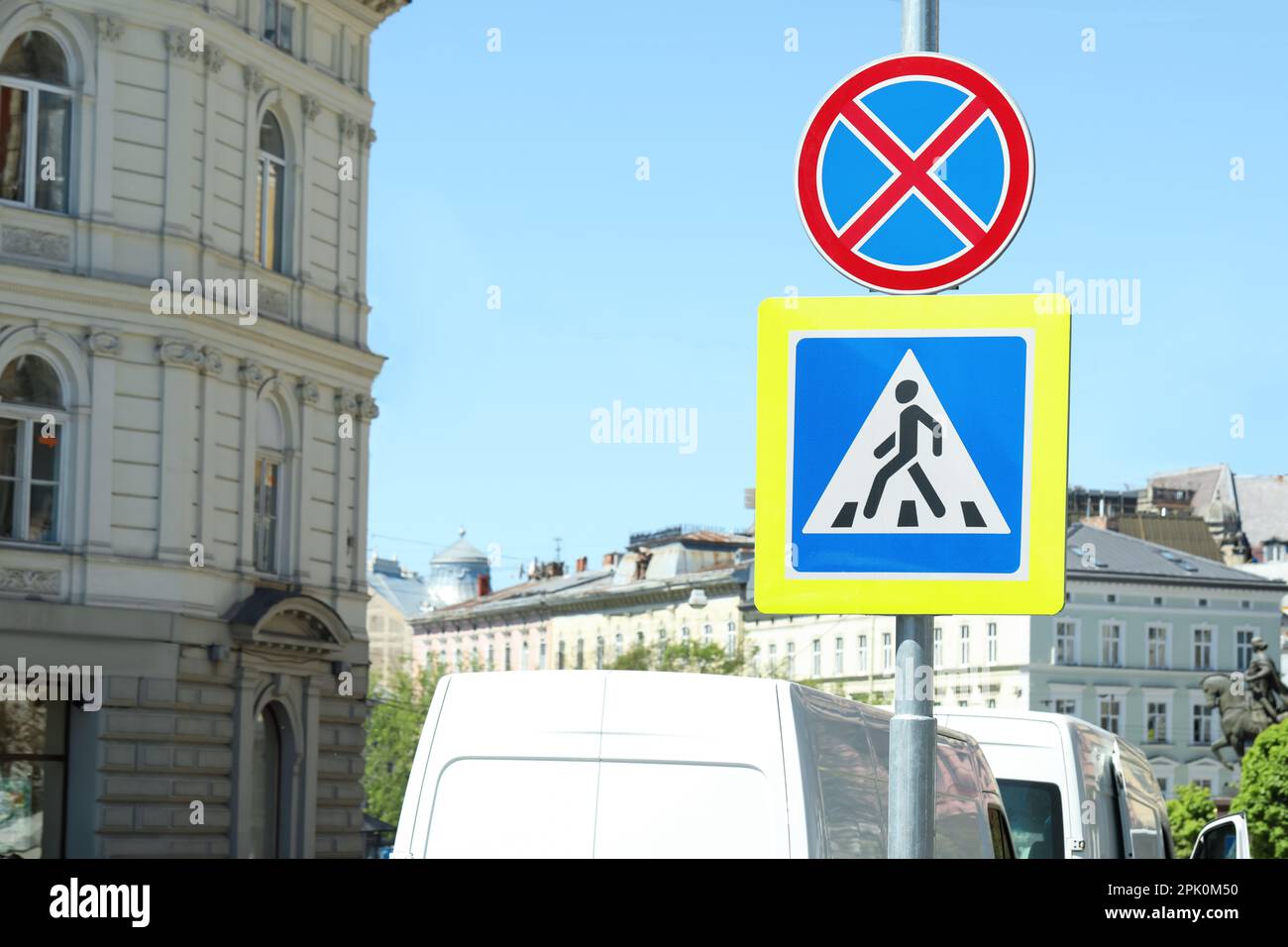 Post with Pedestrian Crossing and No Stopping traffic signs in city on ...