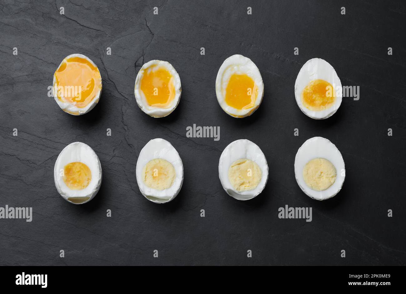 Different readiness stages of boiled chicken eggs on black table, flat ...