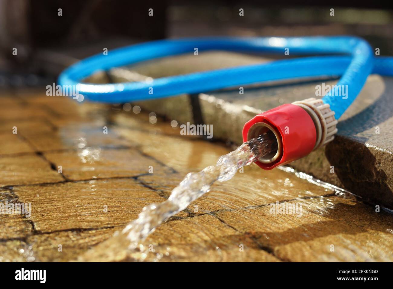 Water flowing from hose on stone floor outdoors, closeup. Space for ...
