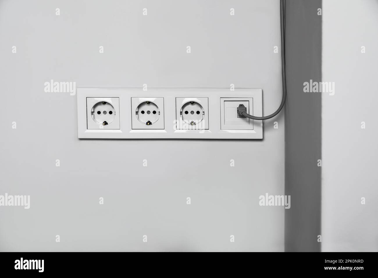 Power sockets with internet cable on white wall. Electrical supply ...
