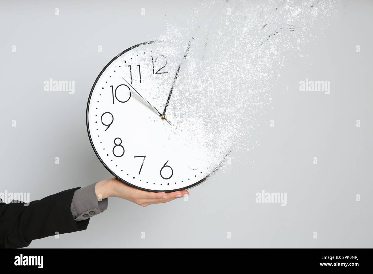 Time is running out. Woman holding vanishing clock against light grey ...