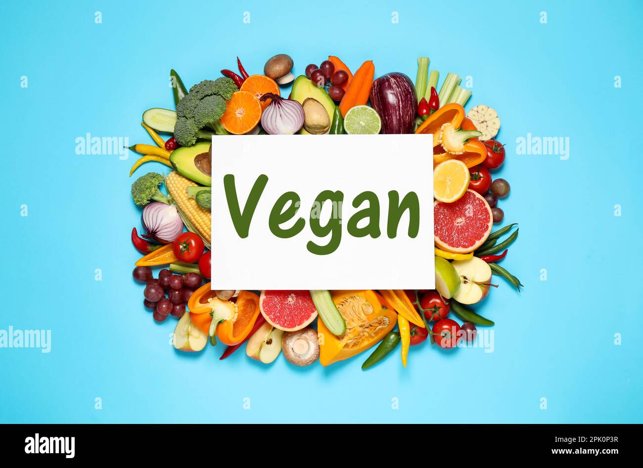 Paper card with word Vegan, fresh vegetables and fruits on turquoise ...