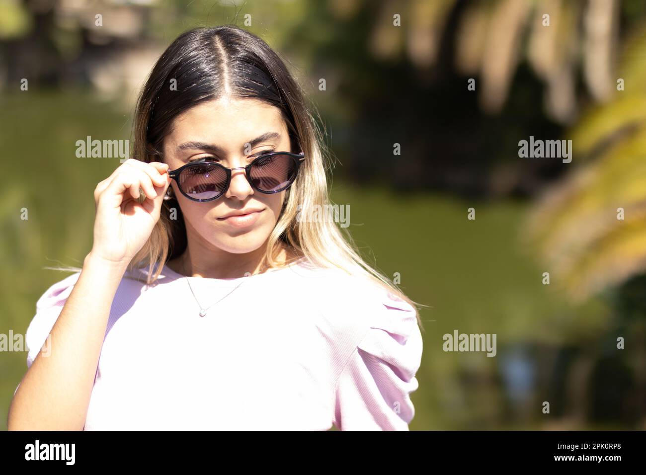 Teenager looking to the side raising his sunglasses in an expression of ...