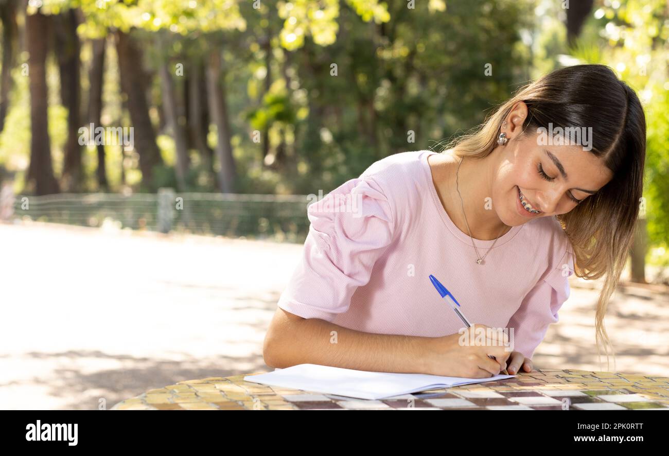 Entertained teenager girl writing in a book. Smiling. denture with ...