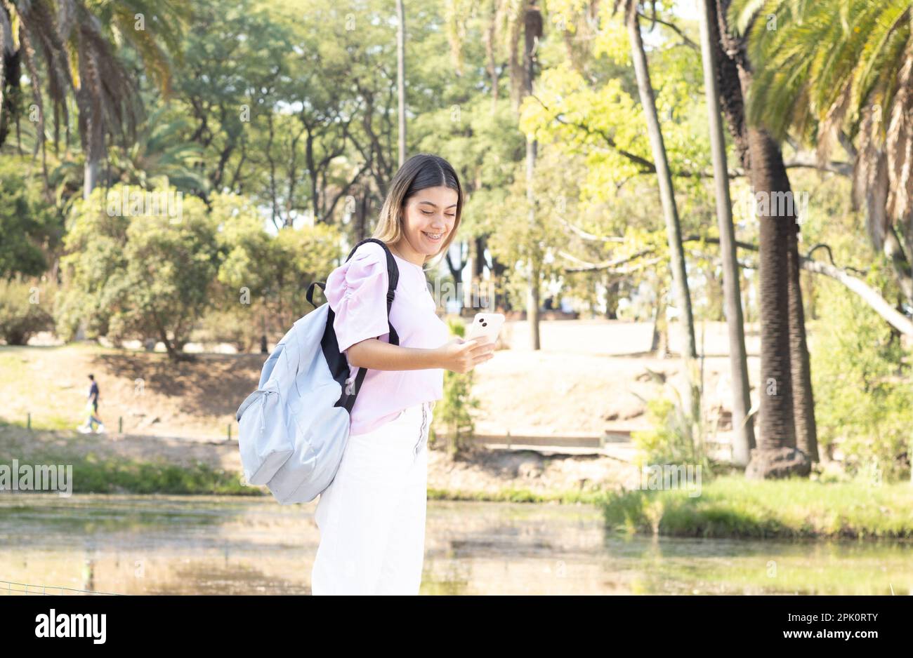 Funny teenager girl walking in the park while watching at the ...