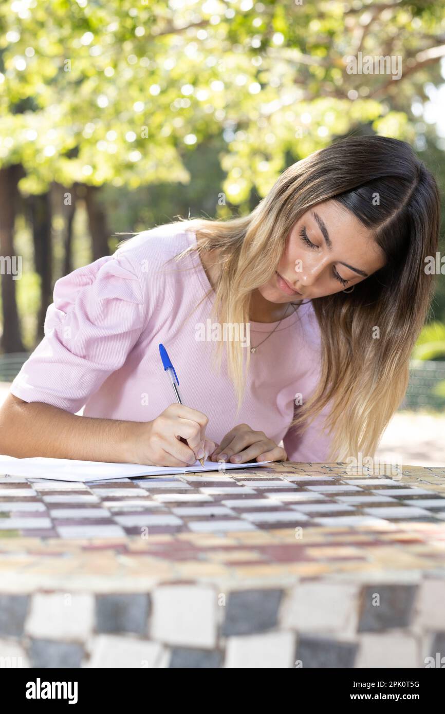 Concentrated teenager girl writing in a book. Vertical format Stock ...