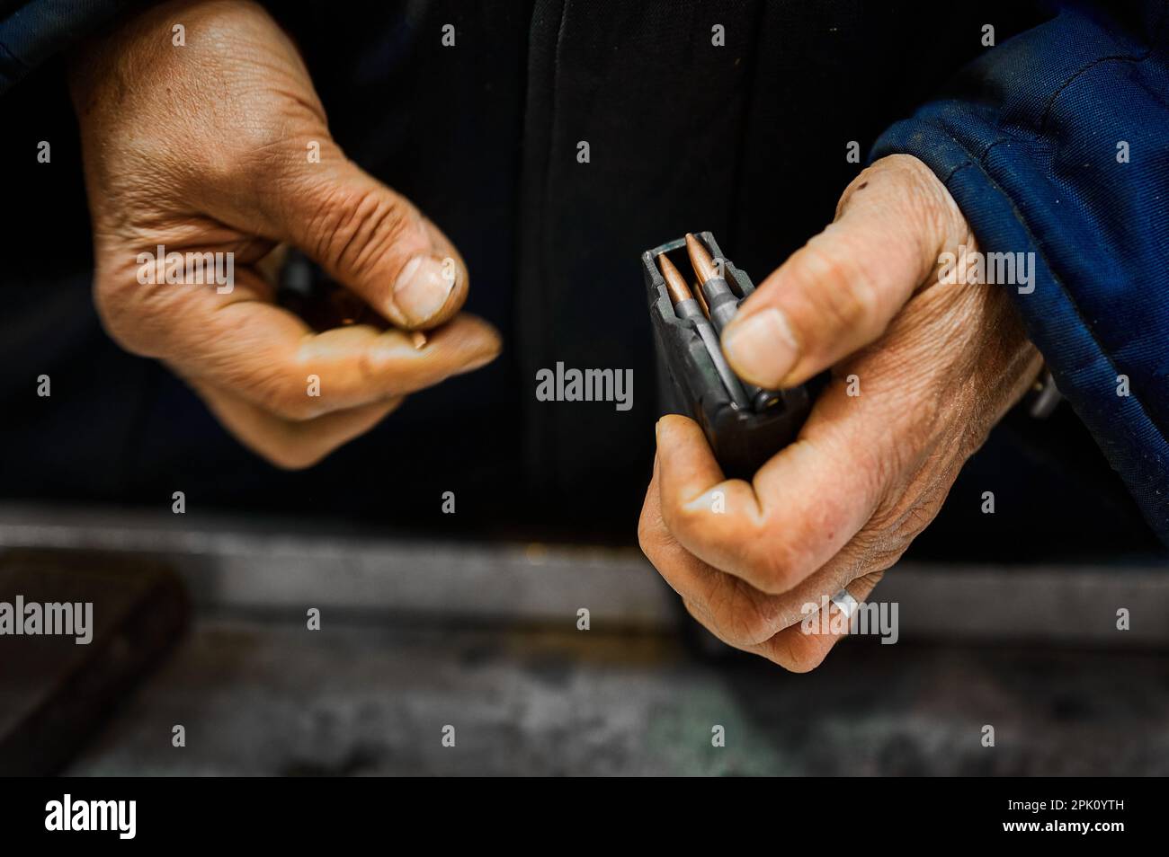 Senior worker puts bullets into gun magazine at factory Stock Photo - Alamy
