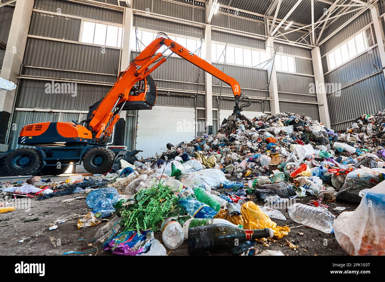 Excavator grabs trash in warehouse of waste processing plant Stock ...
