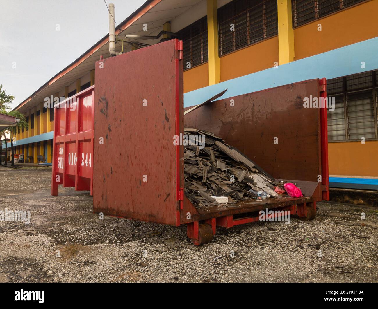 Metal garbage container with piles of garbage outside the building ...