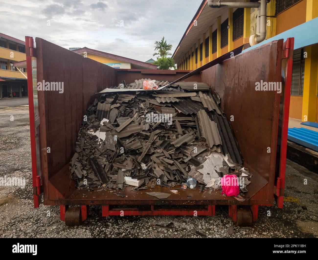 Metal garbage container with piles of garbage outside the building ...