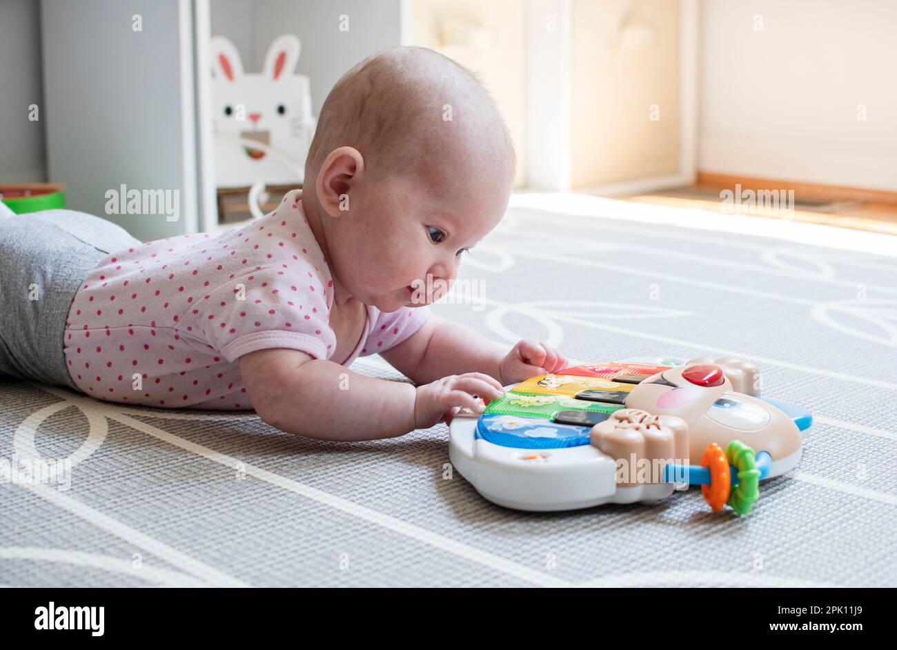 Little caucasian newborn baby girl playing with a piano toy on the ...