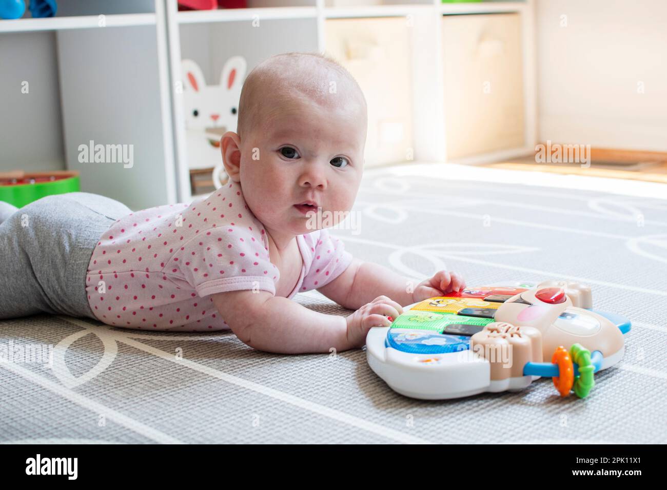Little caucasian newborn baby girl playing with a piano toy on the ...