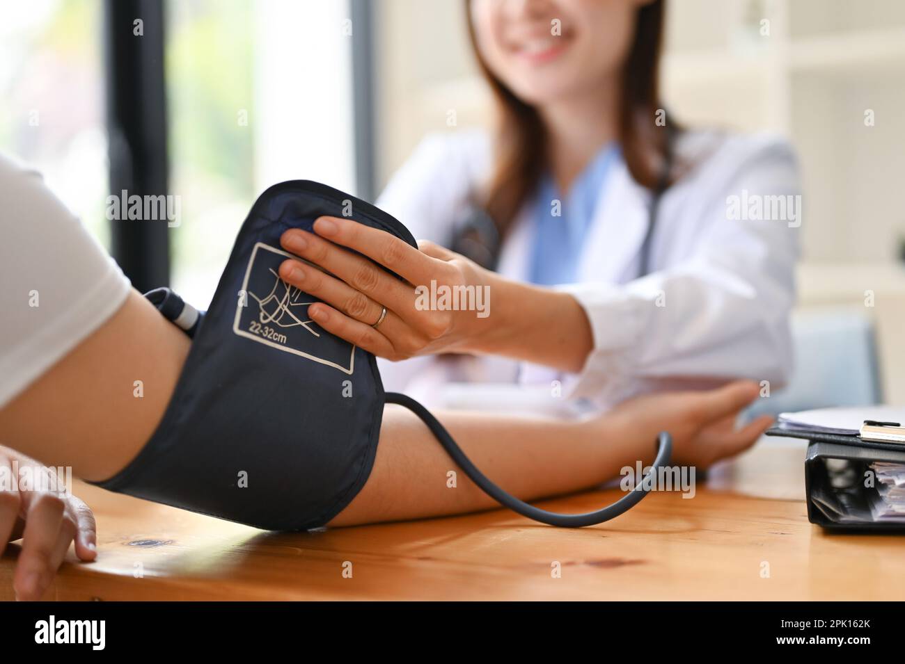 Close-up image of an Asian female doctor checking patient's pulse, heart rate and blood pressure ...