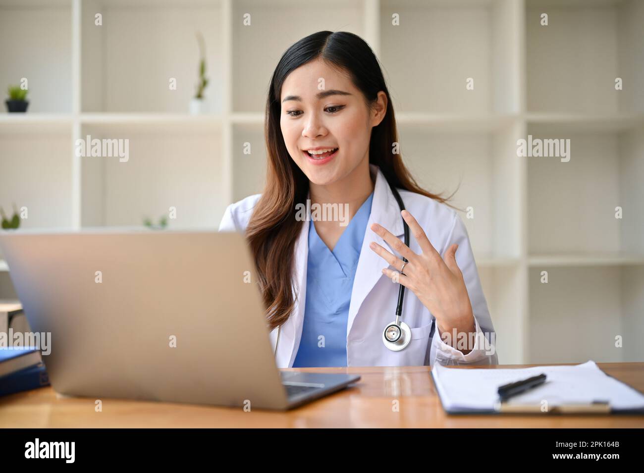 Professional millennial Asian female doctor is having online medical ...