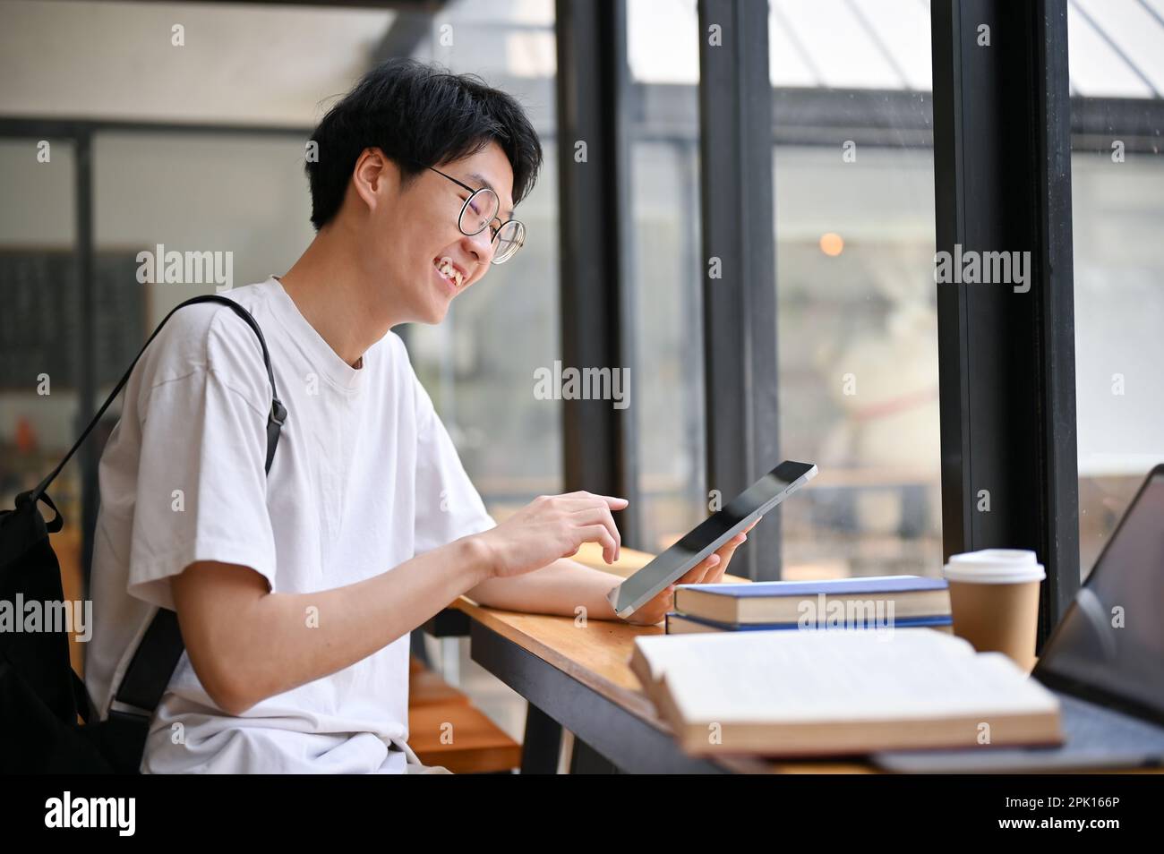 Smart and handsome young Asian male college student using his digital ...
