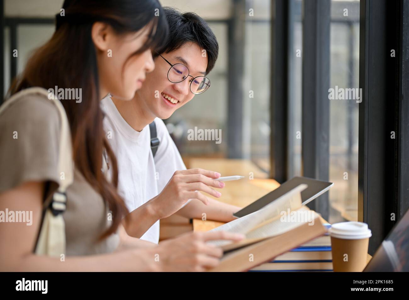 Handsome and smart young Asian male college student tutoring history to ...