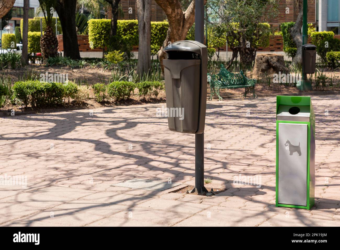 Container for animal waste right next to a garbage container, which is ...